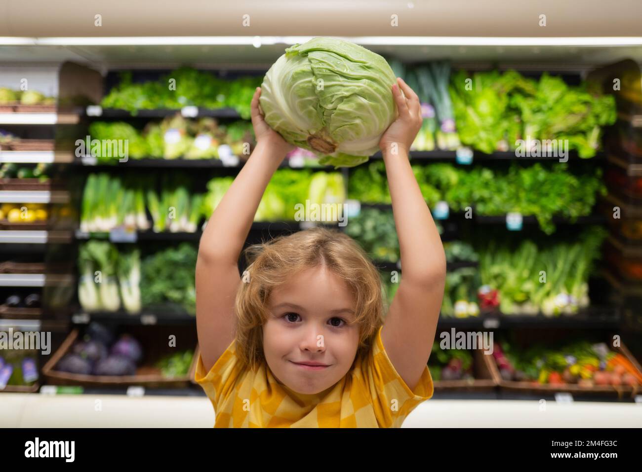 Child with cabbage. Kid in a food store or a supermarket. Little kid ...