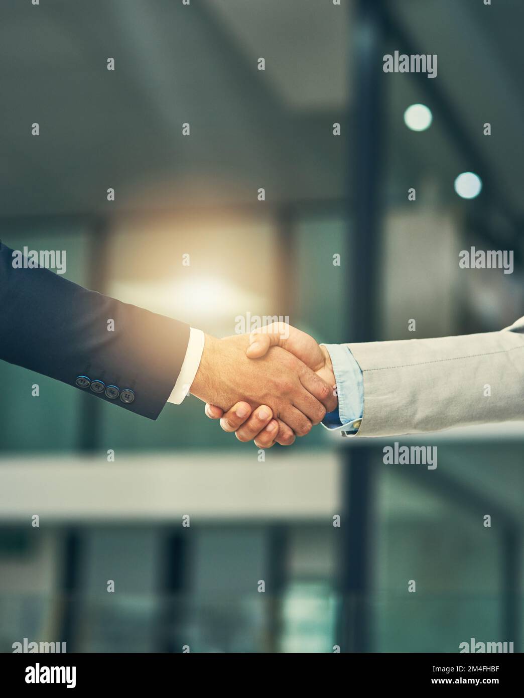 Merge and make it happen. two businessmen shaking hands in a modern ...