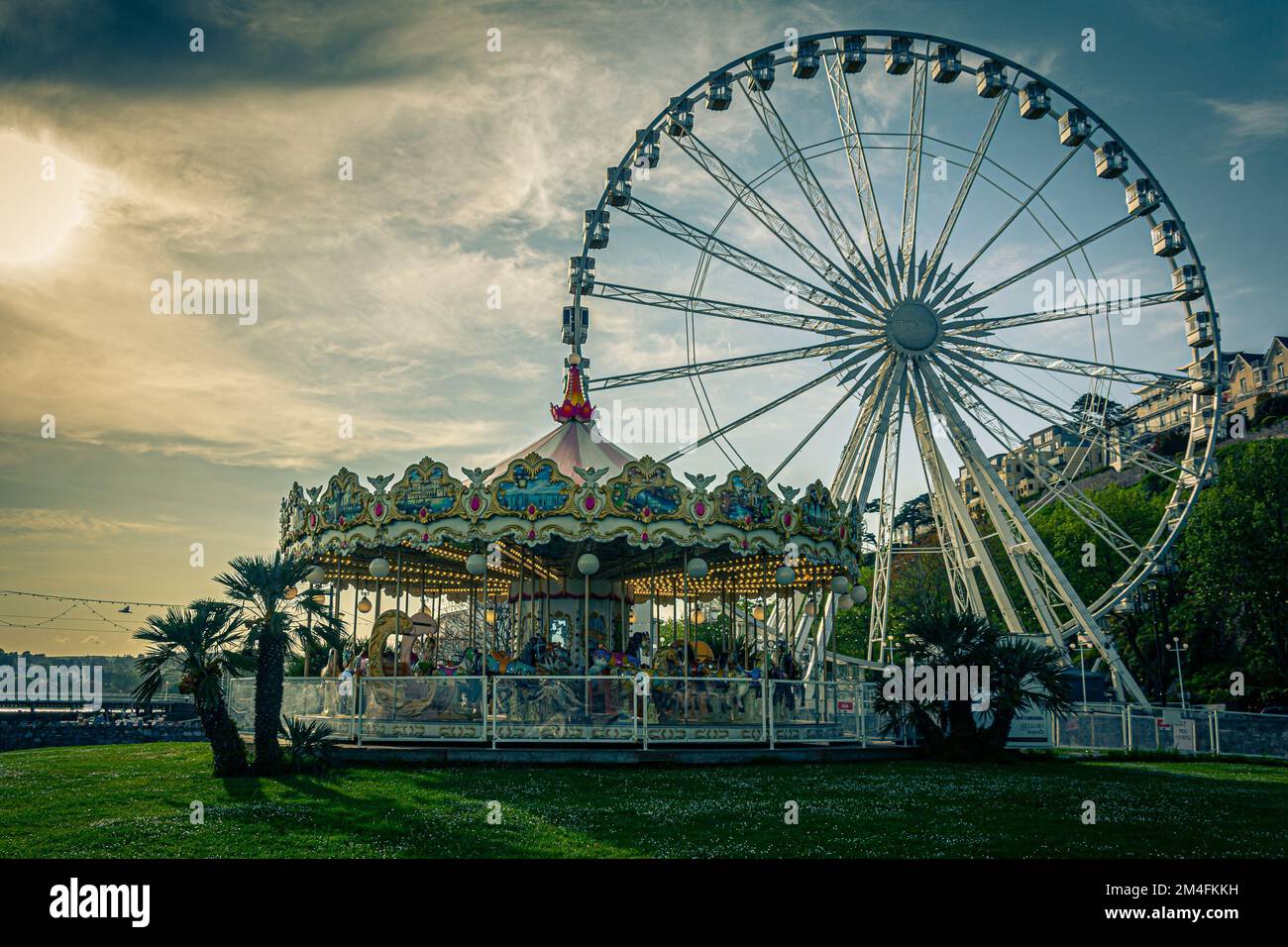 The big wheel and set of gallopers in Torquay, Torbay, UK during sunset ...
