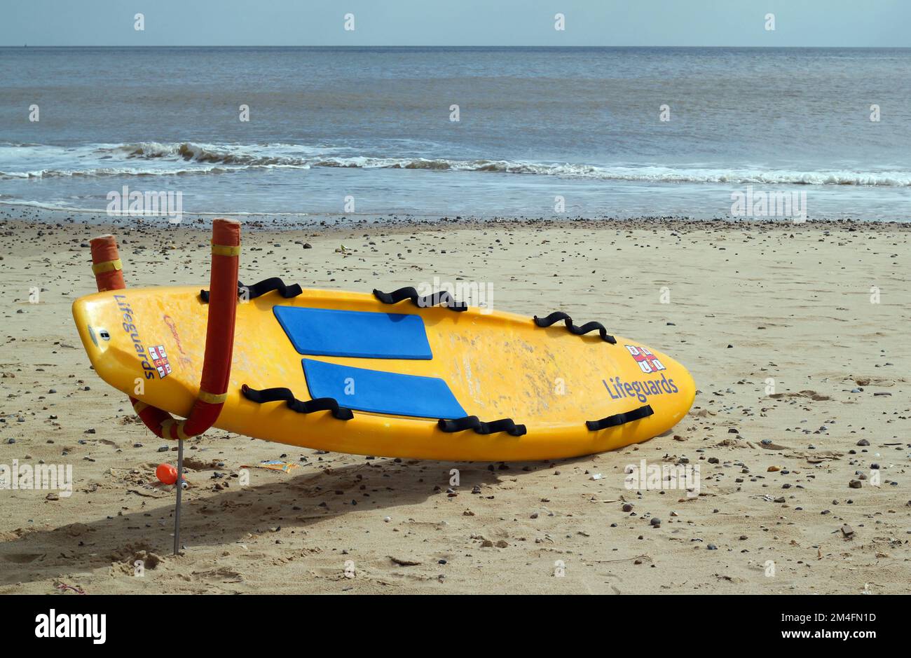 RNLI bodyboard on a beach ready for use to help a swimmer in distress ...
