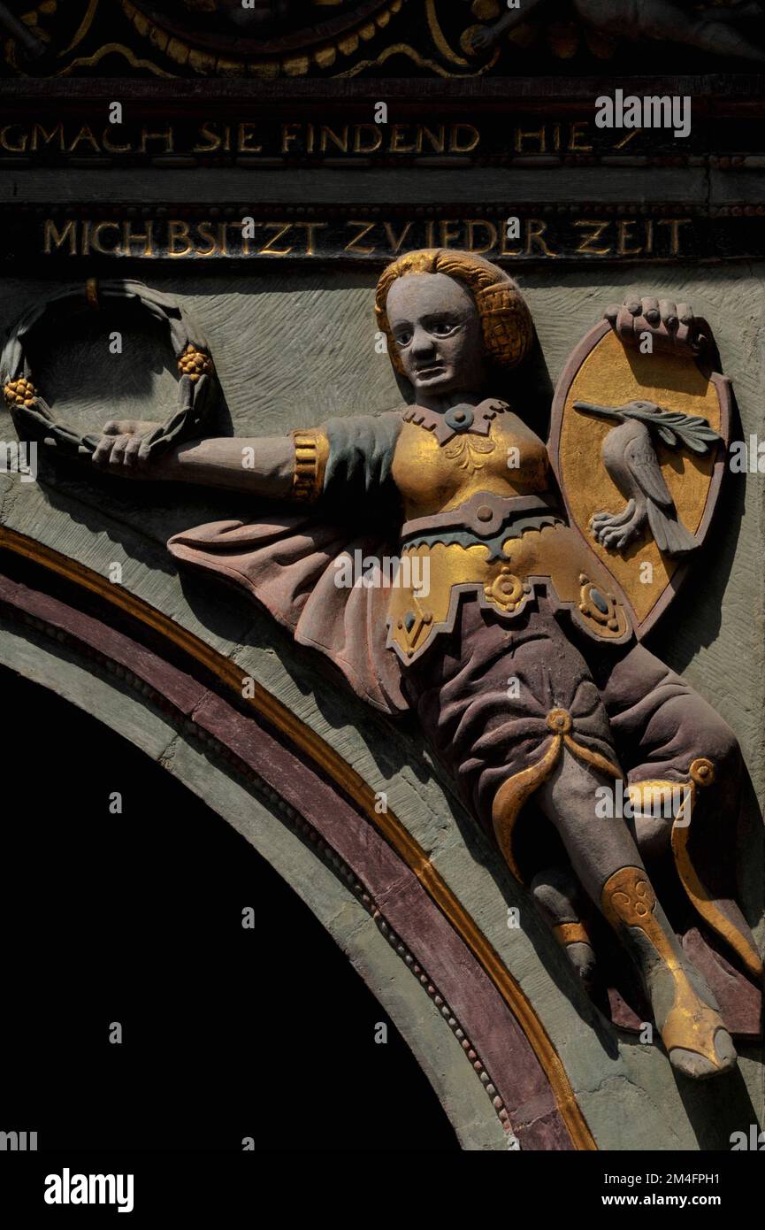 Stern-faced woman with golden hair holds a laurel wreath and an ...