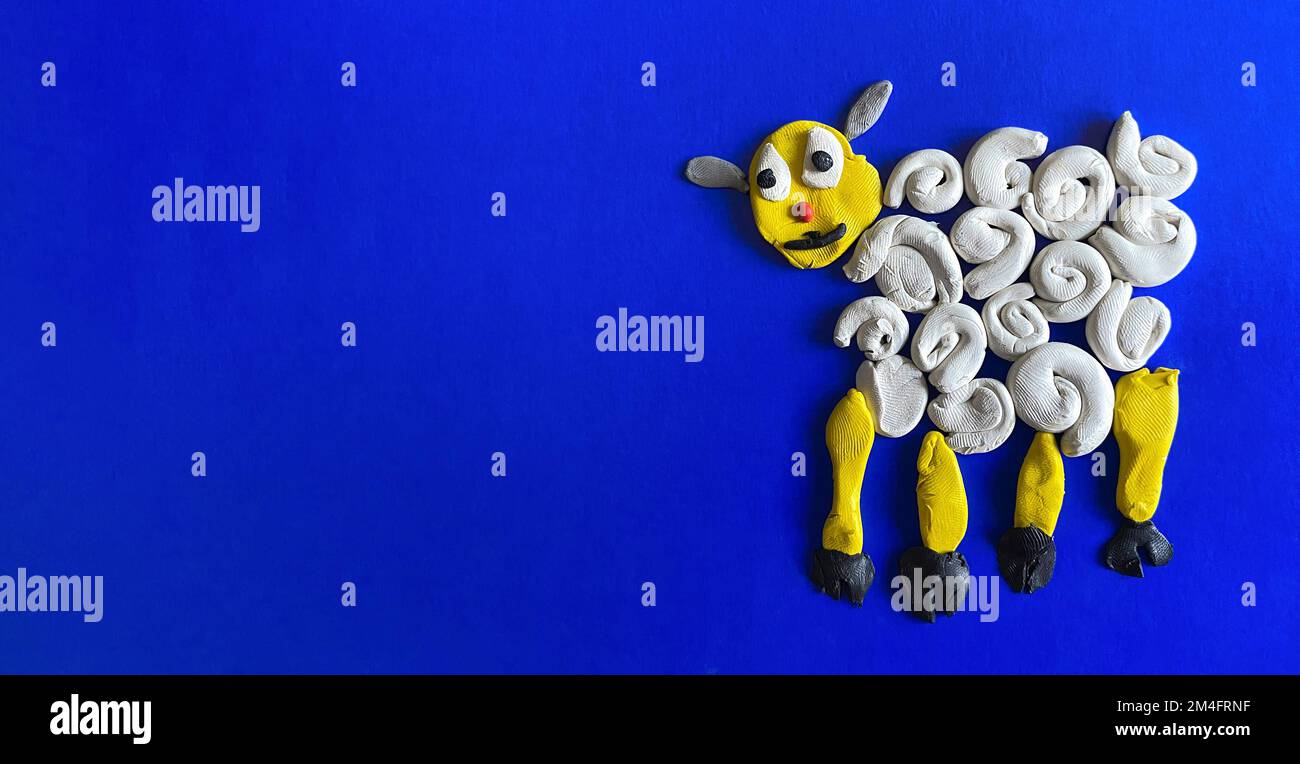 Sheep molded from plasticine on the blue background, selective focus ...