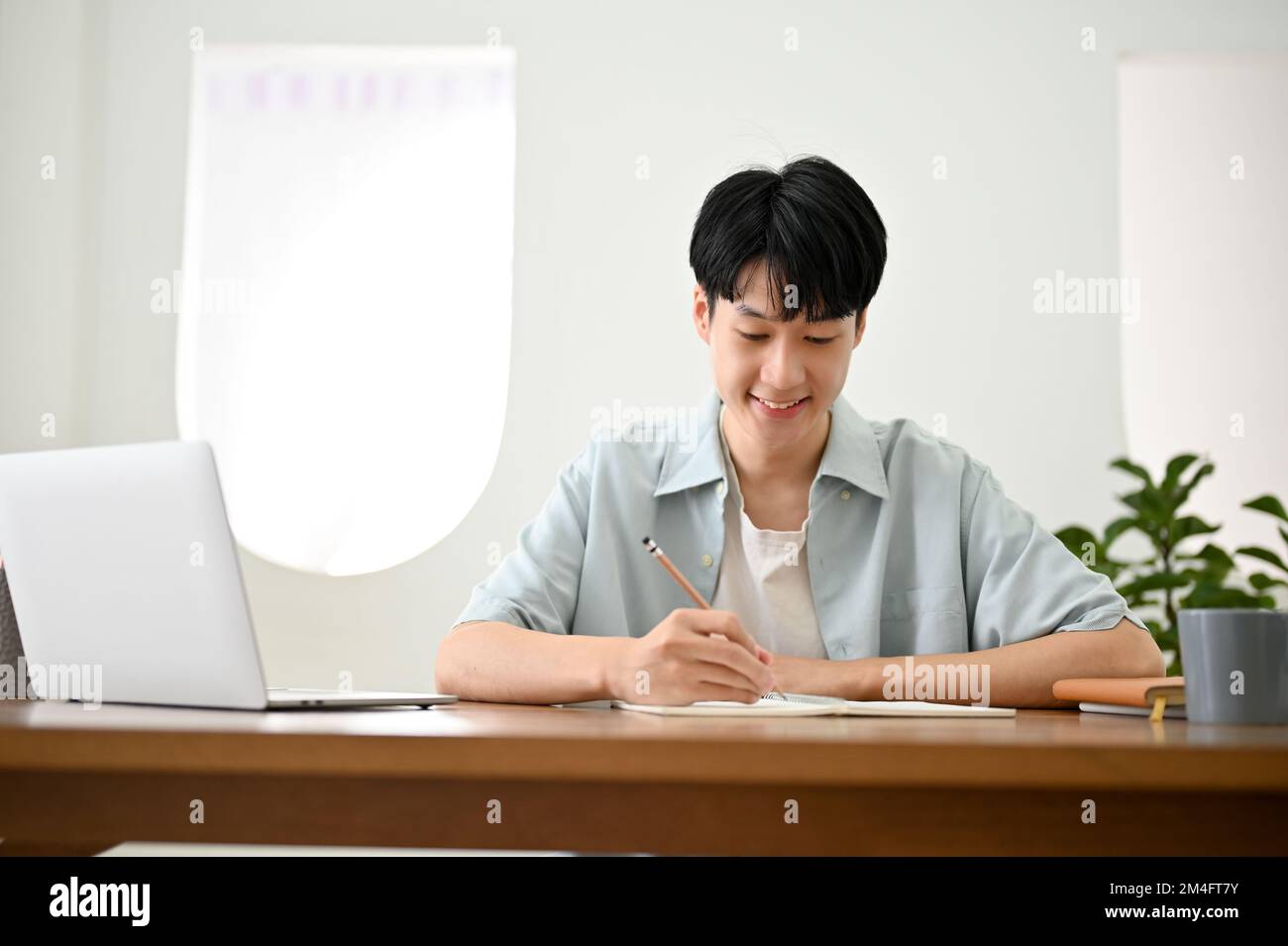 Handsome young Asian male college student focusing on his homework ...