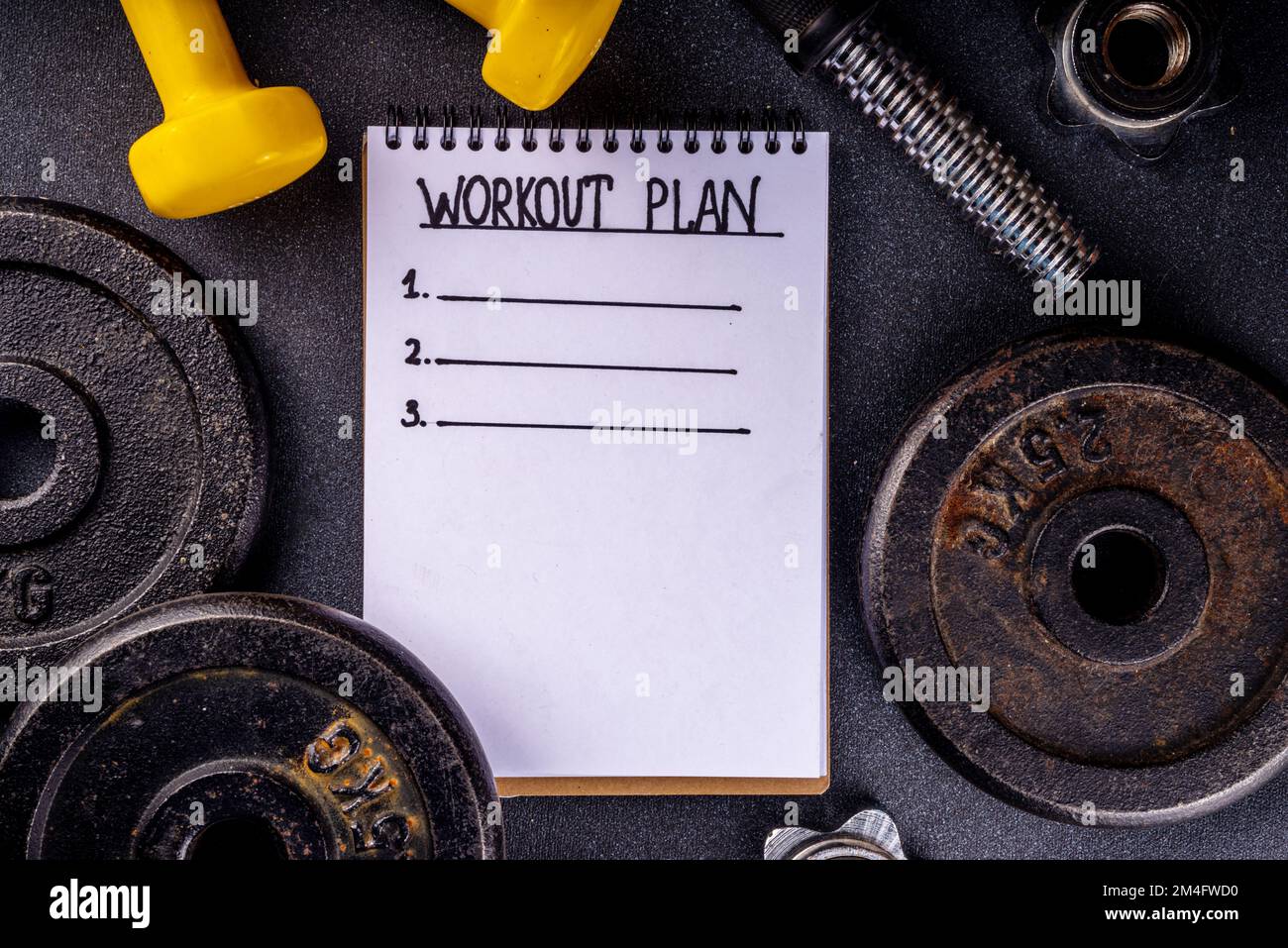 Fitness or bodybuilding background. Old hard iron dumbbells, small colorful dumbbells, notepad ...