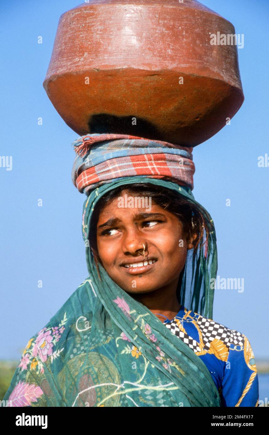 Young girl carrying water from the well to her house Stock Photo - Alamy