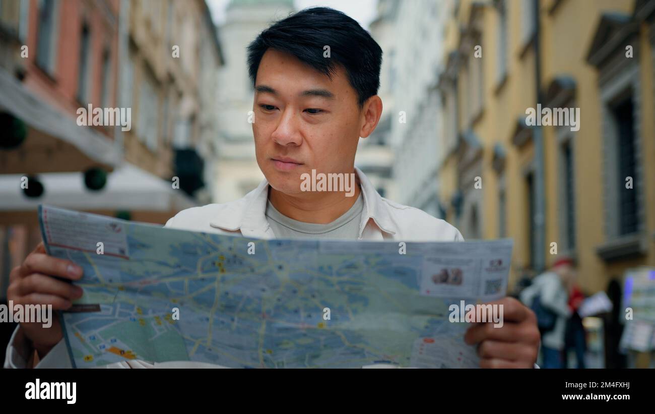 Asian male tourist traveling in new city standing outdoors looking at ...