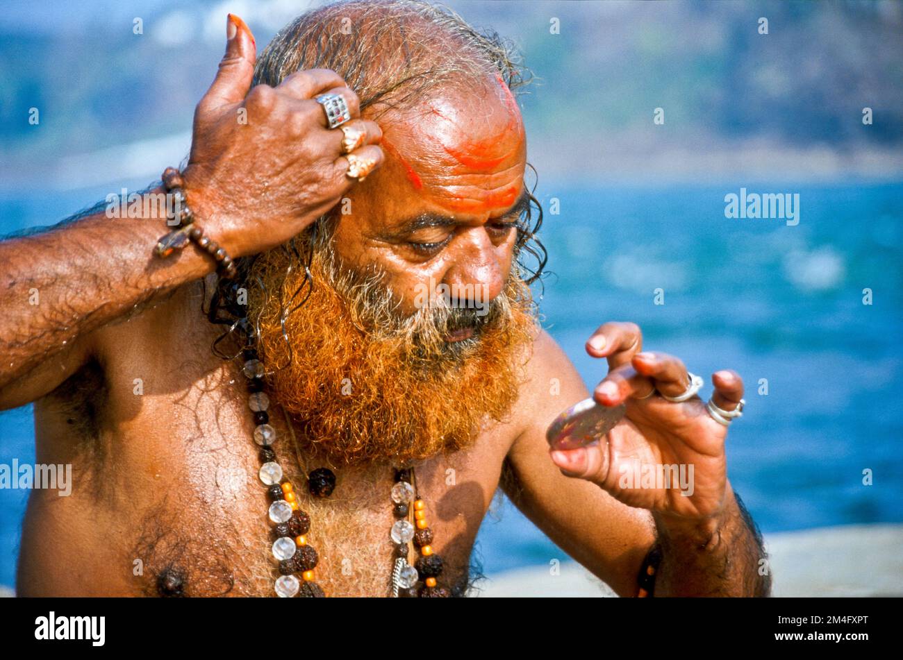 Sadhu, holy man, doing his washing and praying ceremony in the morning ...
