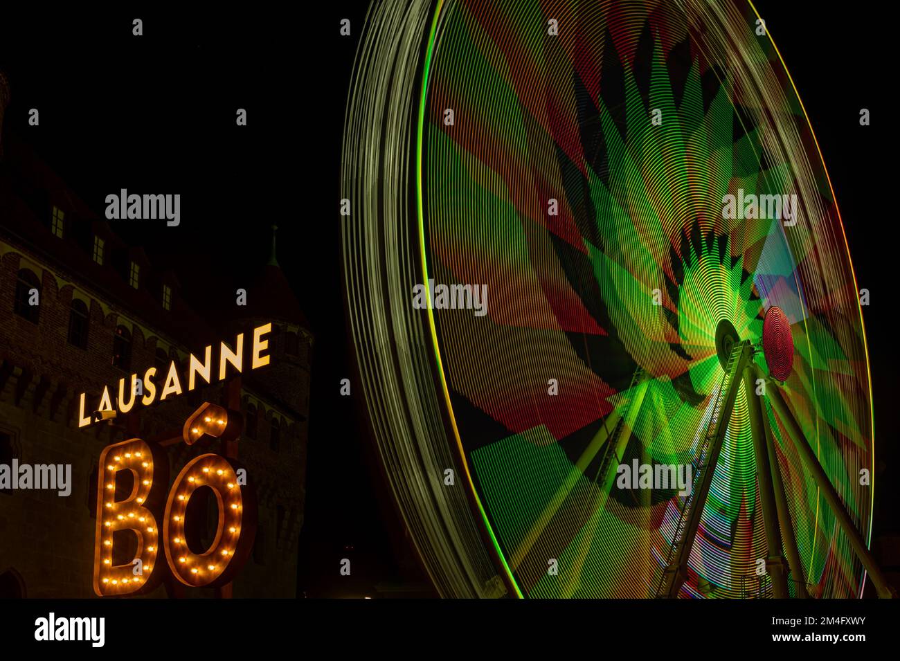 Ferries wheel rotating at night with lights at amusement park. Bo light ...