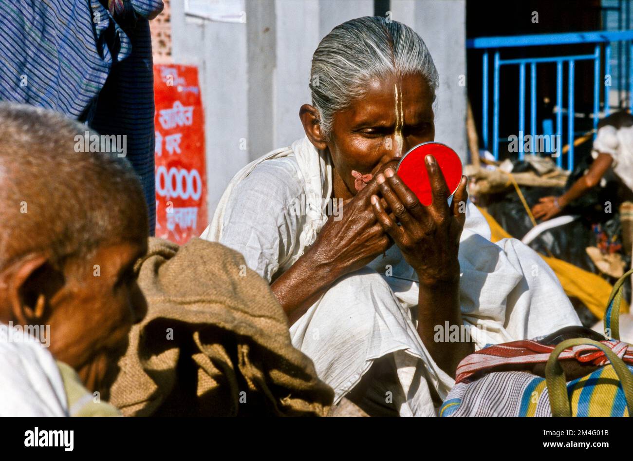 Female Krishna-Sadhu applying her tilak as part of the morning pooja ...