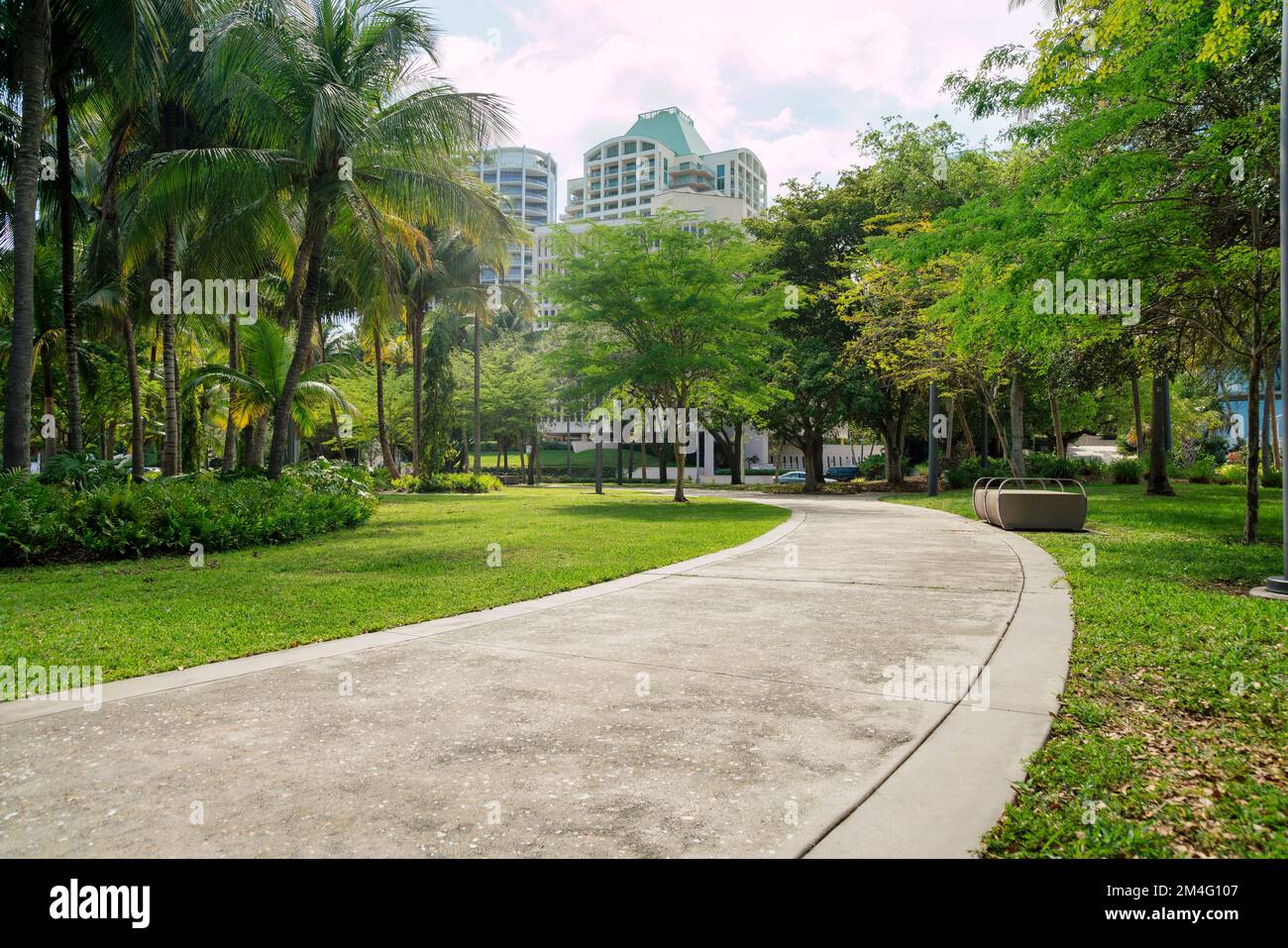 Concrete path in a park with grass and trees near the condominiums at ...