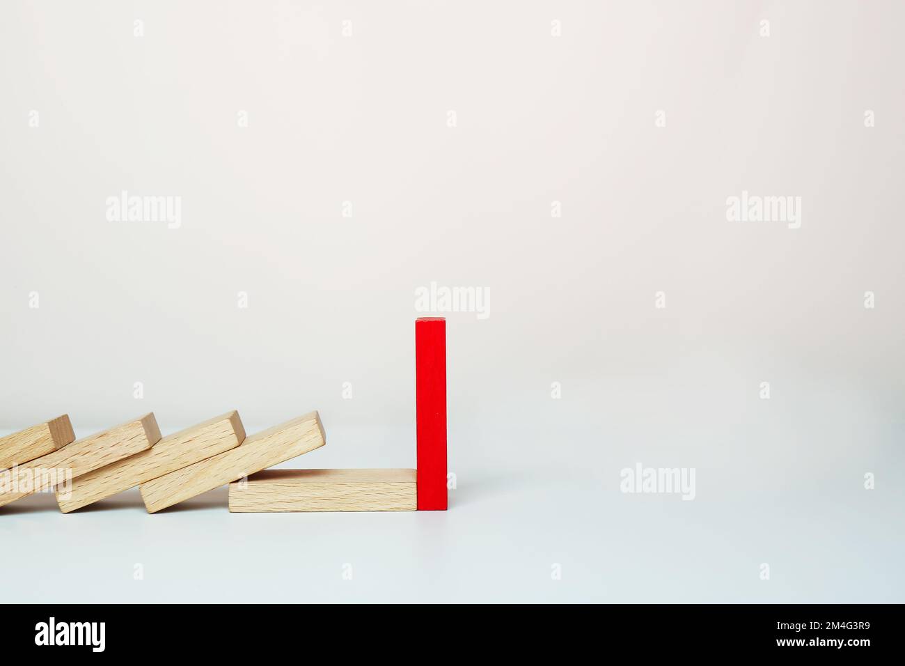 One red domino stands, and other wooden dominoes fall in a row. Chain ...