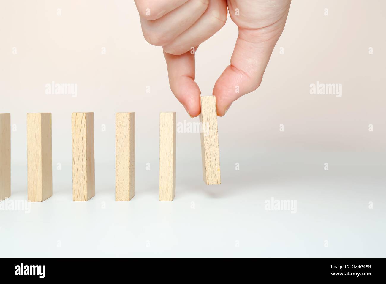 A business concept with a domino effect. The hand puts dominoes to make ...