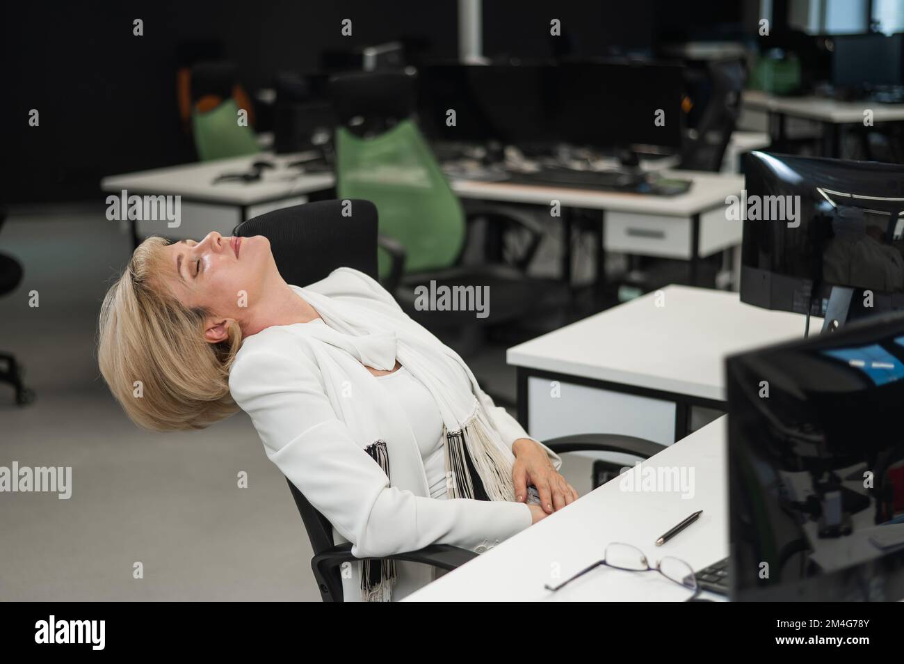Caucasian blonde woman sleeping at her desk in the office Stock Photo ...