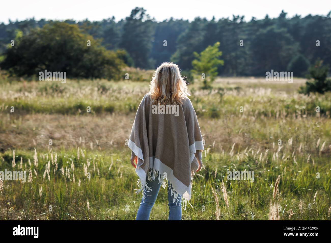 Boho woman with poncho standing outdoors. Enjoyment of spending time in ...