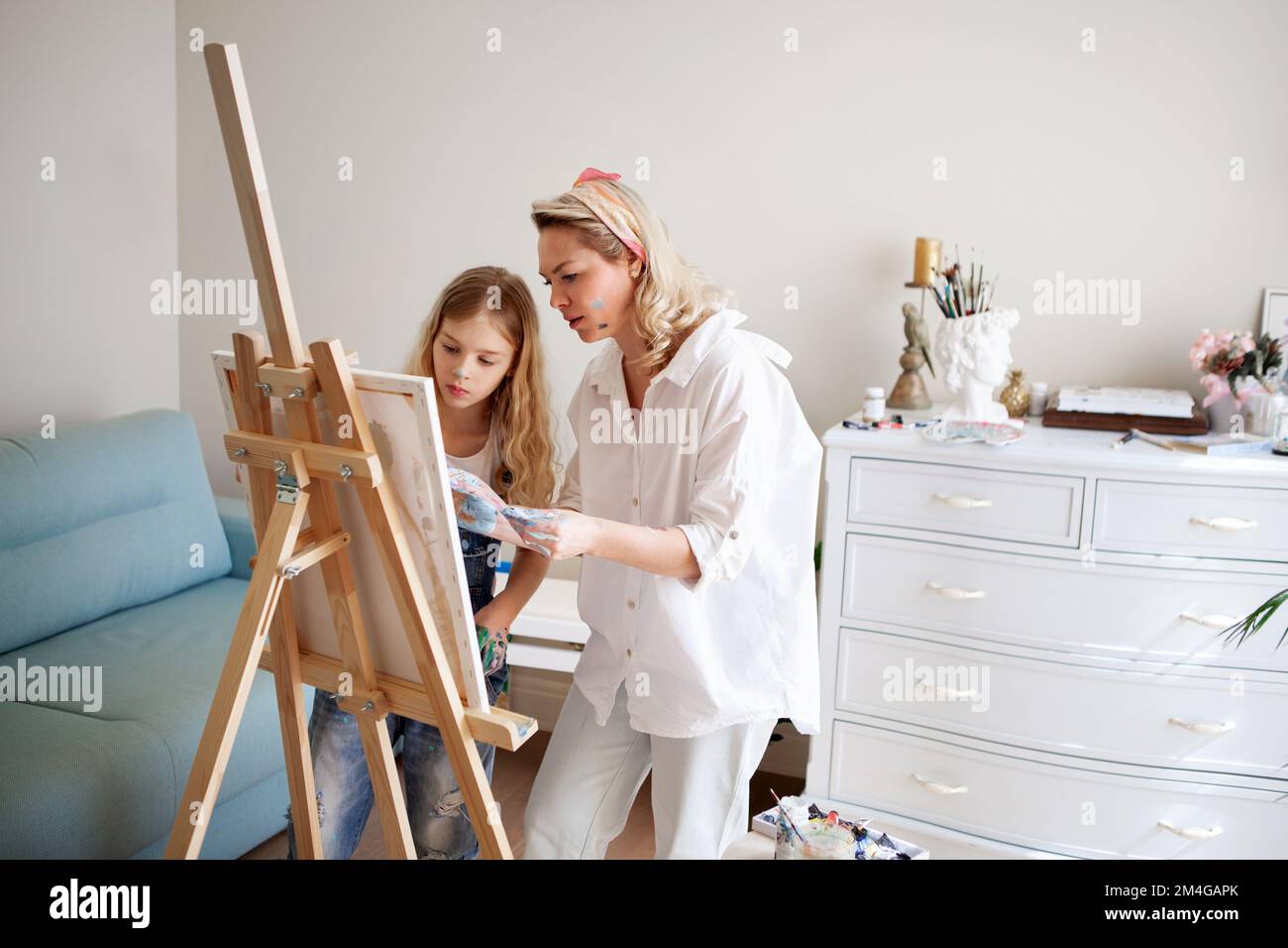 Mother and teenage daughter girl enthusiastically draw picture on ...
