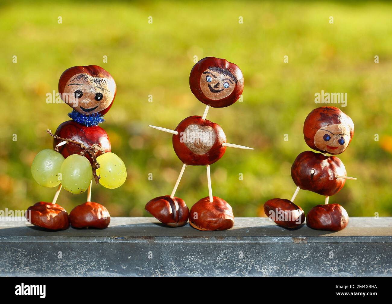 three cute chestnut figures with wine grapes Stock Photo - Alamy