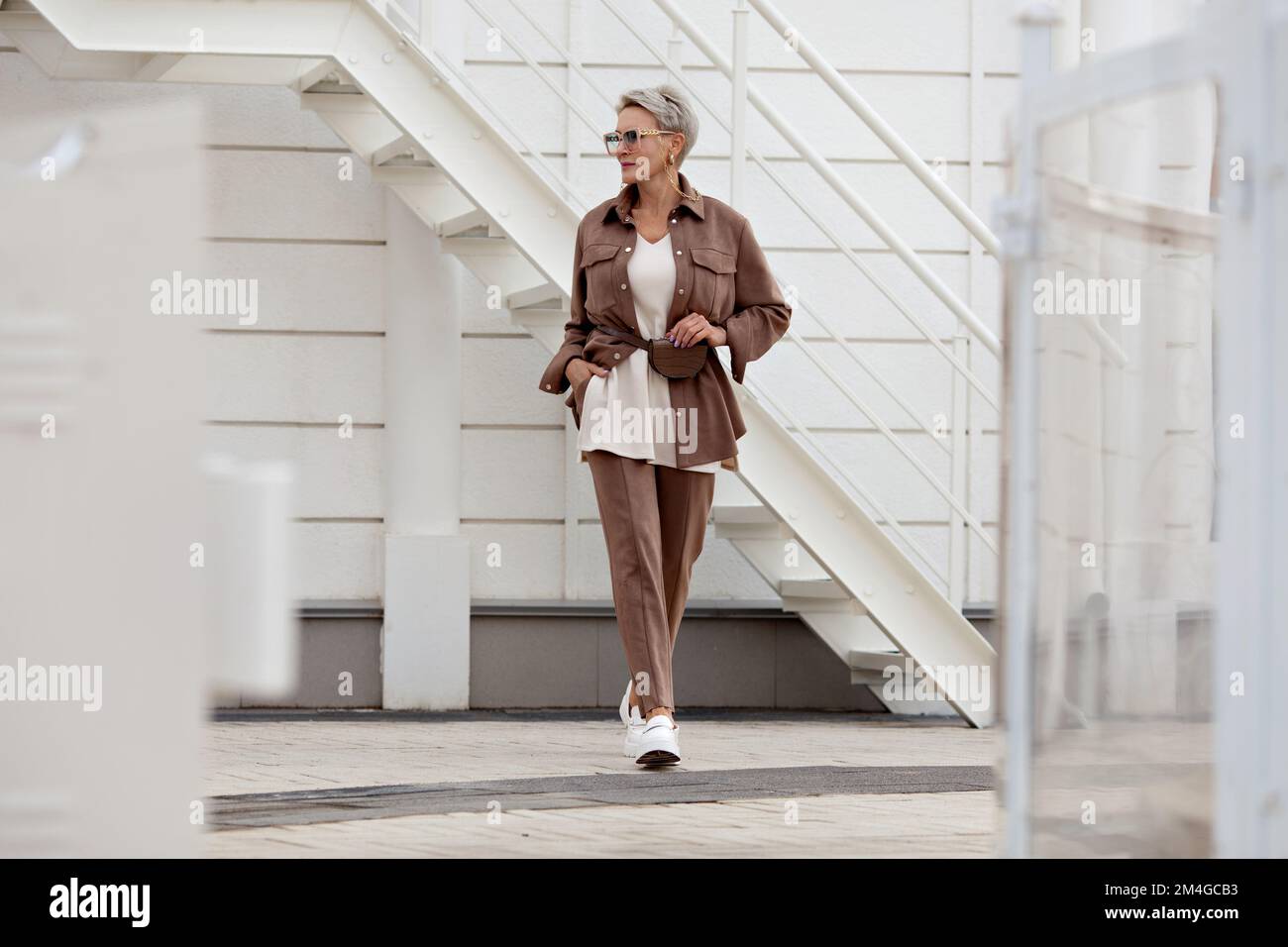 Stylish woman walking city street. Short hair Model wears beige ...