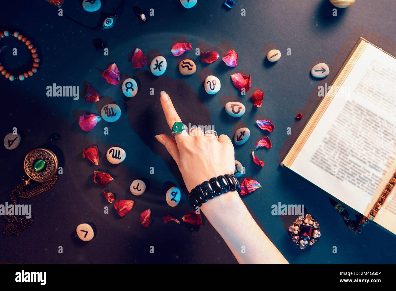 Concept of astrology and horoscope. A woman's hand points to the stones ...