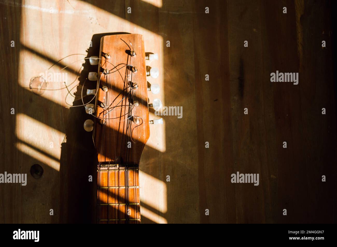 old charango placed on a wooden table lit by the window sun, copy space ...