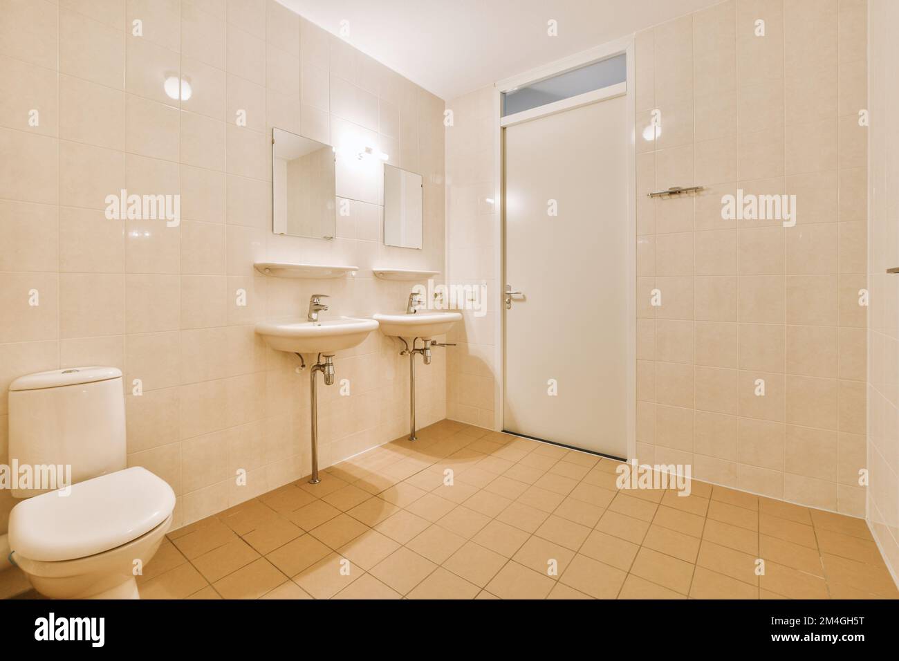 a bathroom with tile flooring and beige tiles on the walls, along with ...