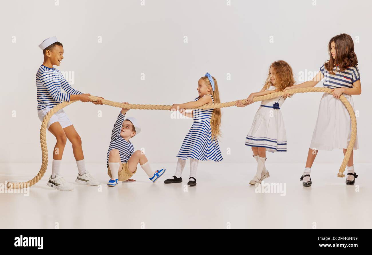 Portrait of children posing in sea style clothes, pulling rope, playing ...