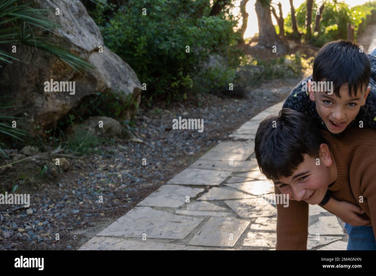 Funny boy climbing on back of cheerful teen brother while spending time ...