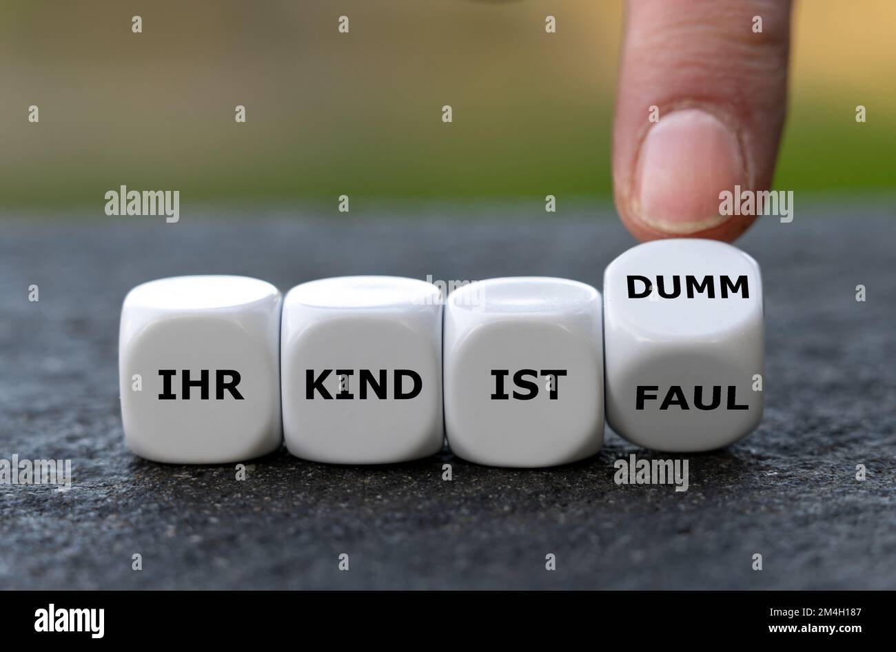 Hand turns dice and changes the German expression 'Ihr Kind ist faul ...