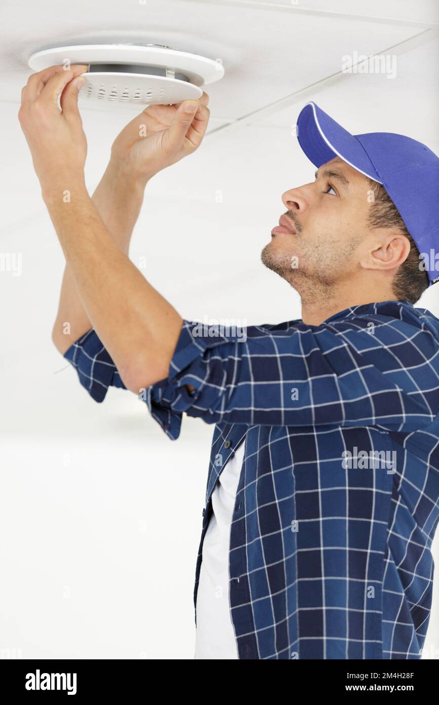 man fixes device to the ceiling Stock Photo - Alamy