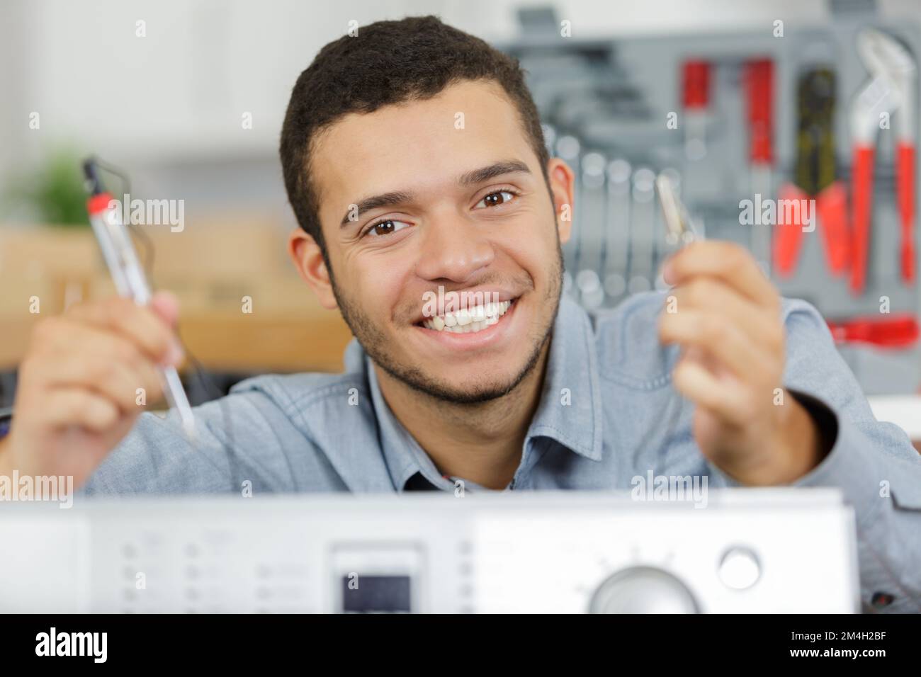 portrait of a happy technician repairing a washing machine Stock Photo ...