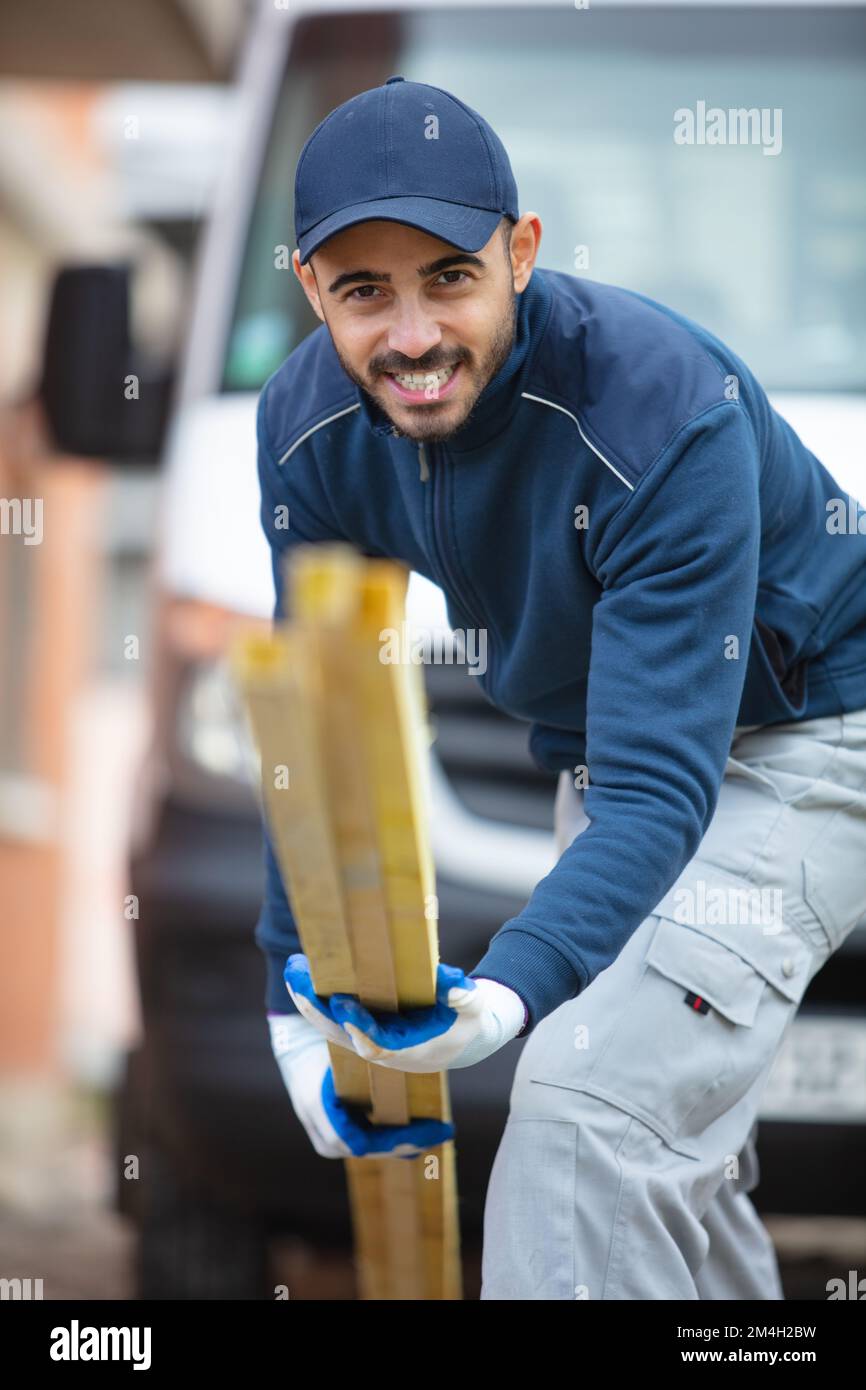 smiling carpenter holding wood planks in a construction site Stock ...