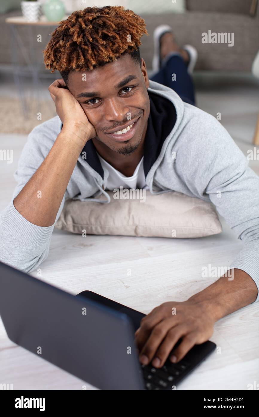 casual young man laying on floor at home with laptop Stock Photo - Alamy