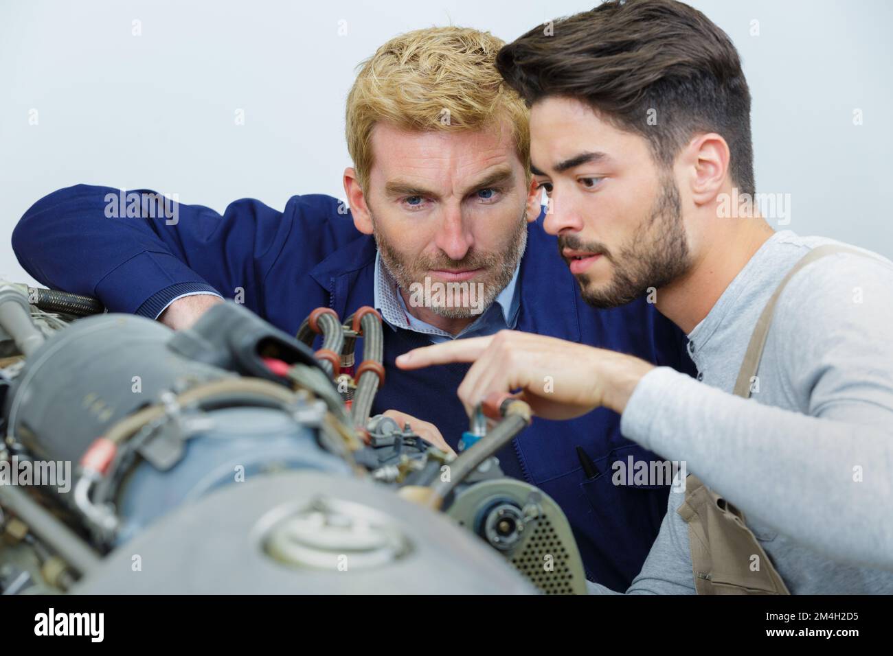 auto mechanic fixing a machine with apprentice Stock Photo - Alamy
