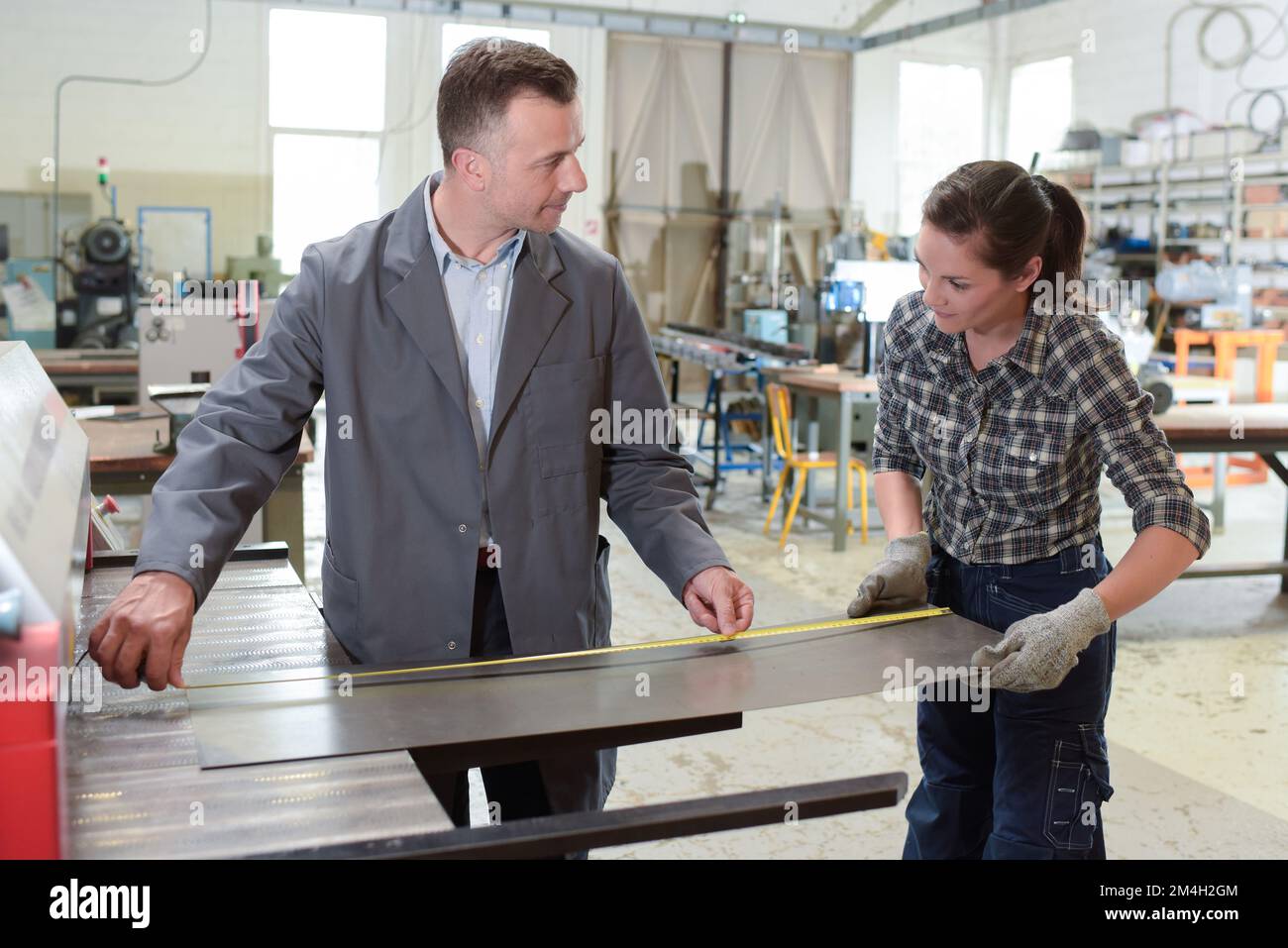 factory manager measuring metal with female employee Stock Photo - Alamy