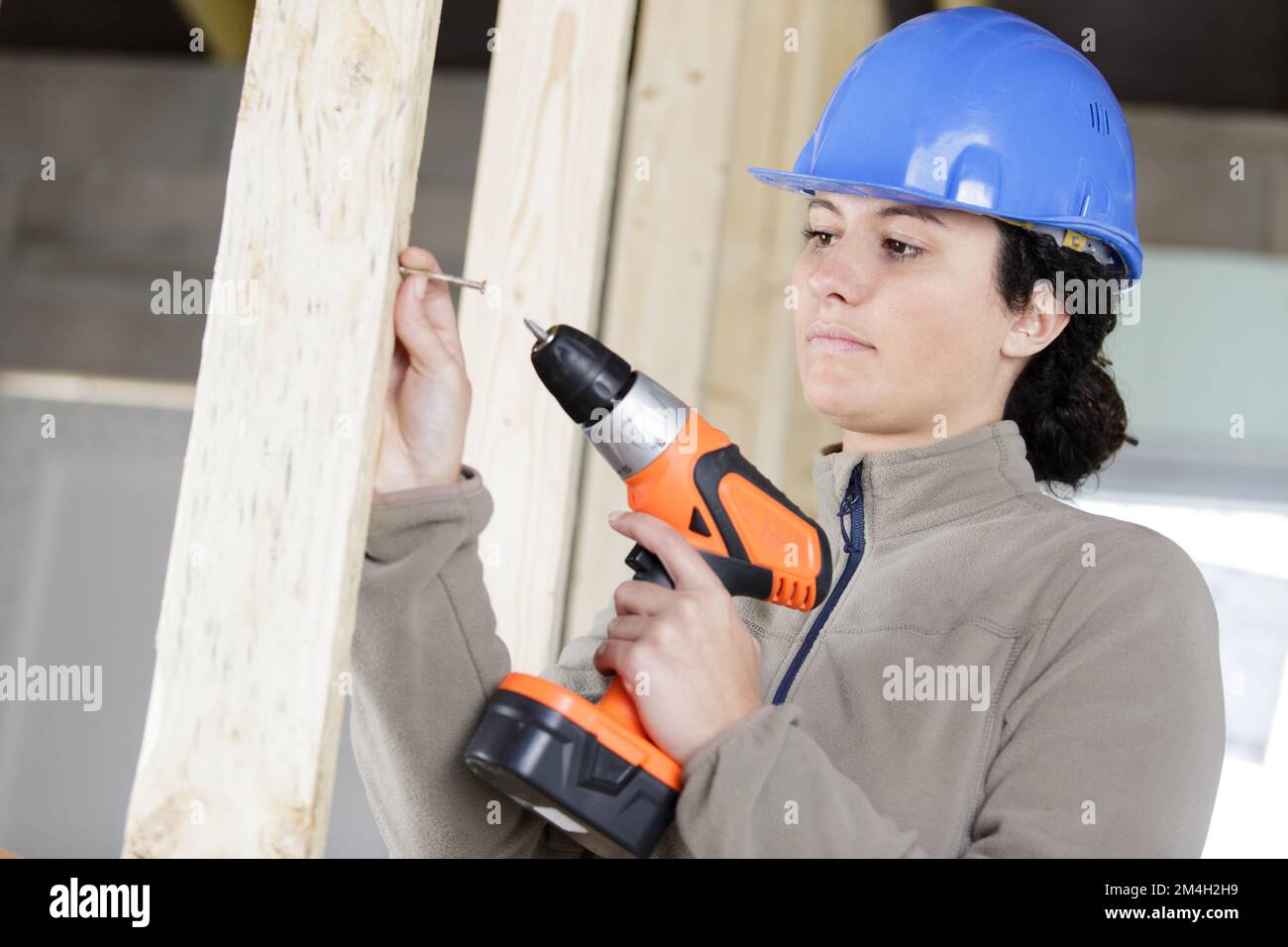 carpenter using a drill on a wood house structure Stock Photo - Alamy