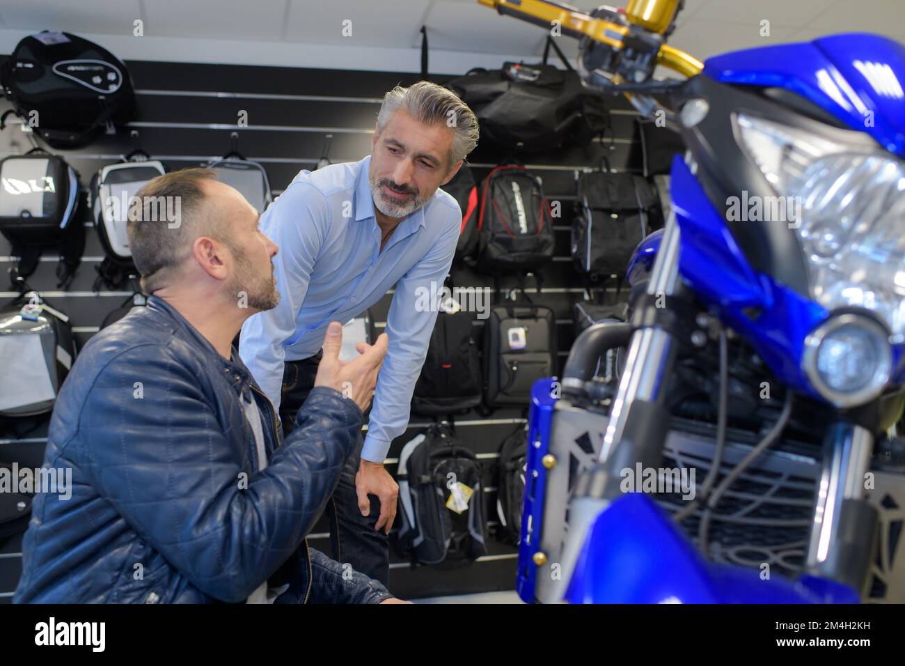 customer listening to motorcycle salon manager near a new motorbike ...