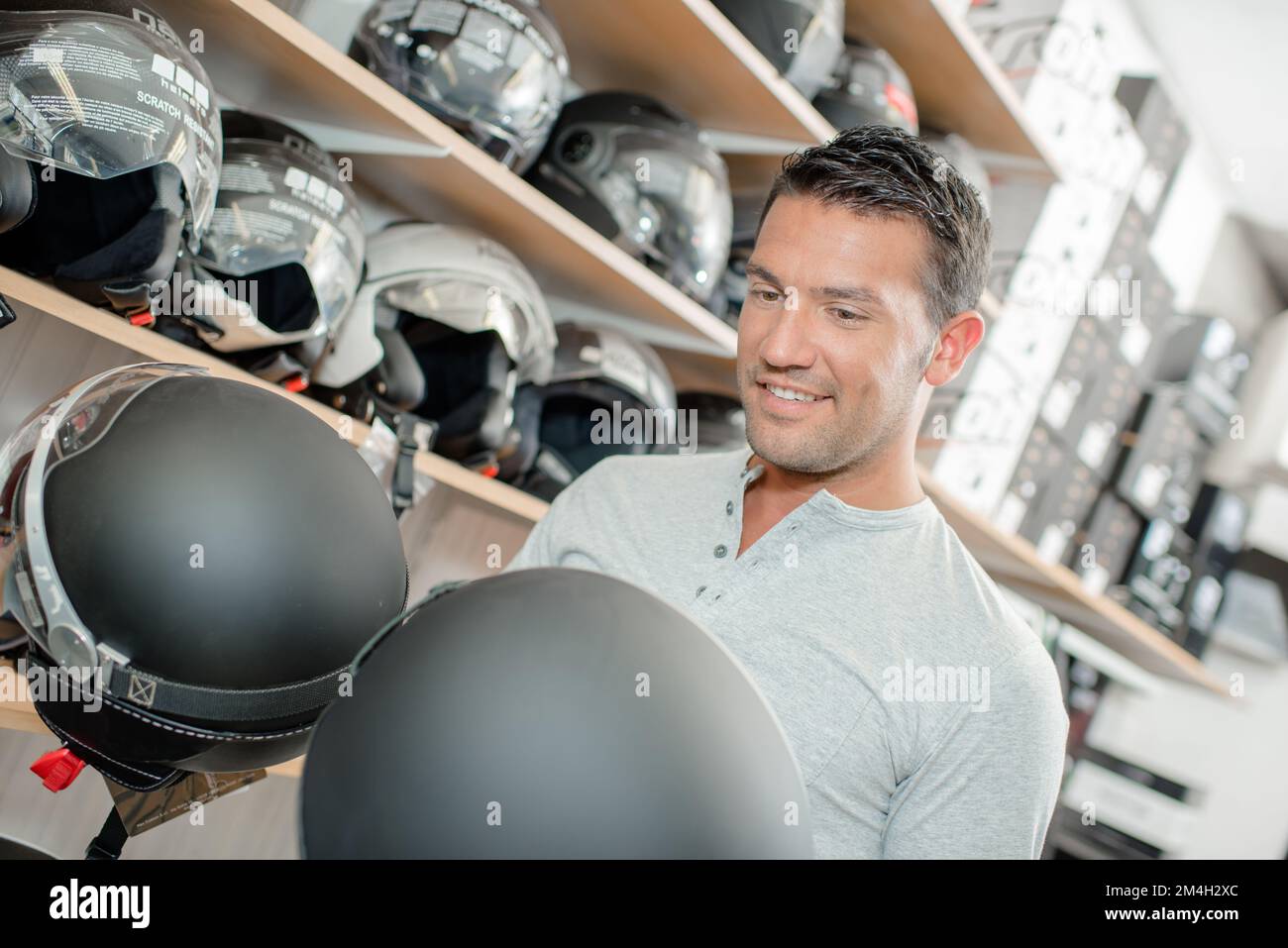 a man is comparing two helmets Stock Photo - Alamy