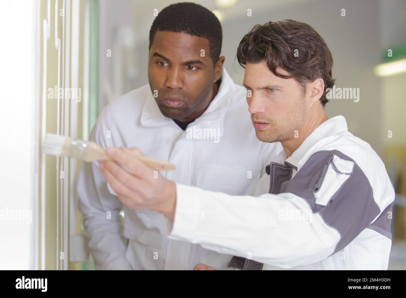 two painters painting a wall Stock Photo - Alamy