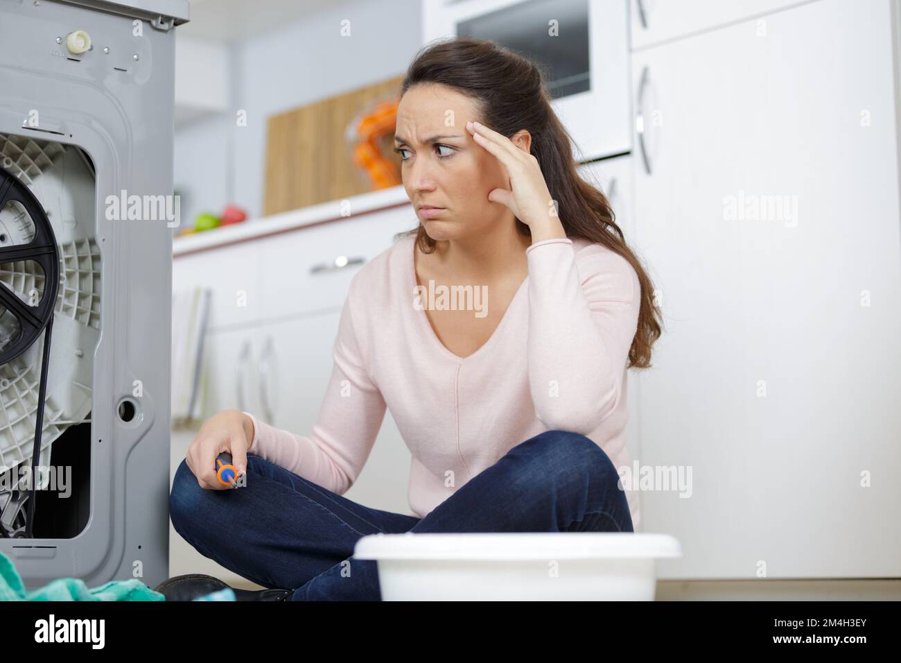 sad woman standing near washing machine Stock Photo - Alamy