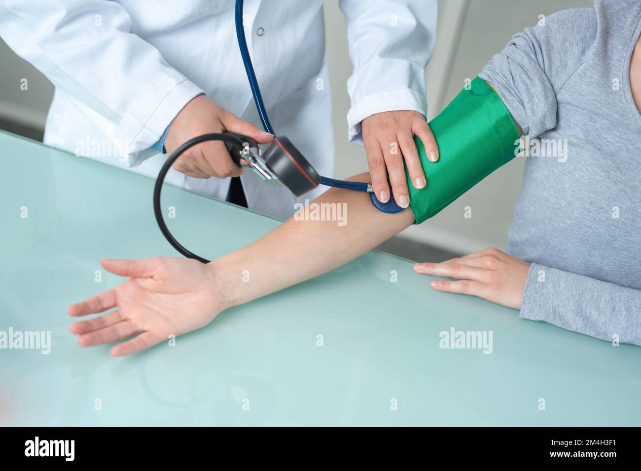 doctor checking female patients blood pressure in clinic Stock Photo ...