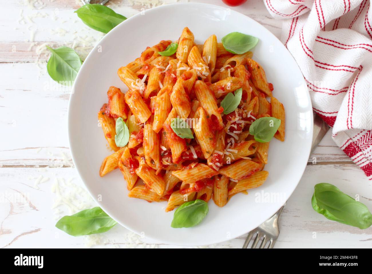 Penne pasta with tomato sauce, parmesan cheese and basil. Top view with ...