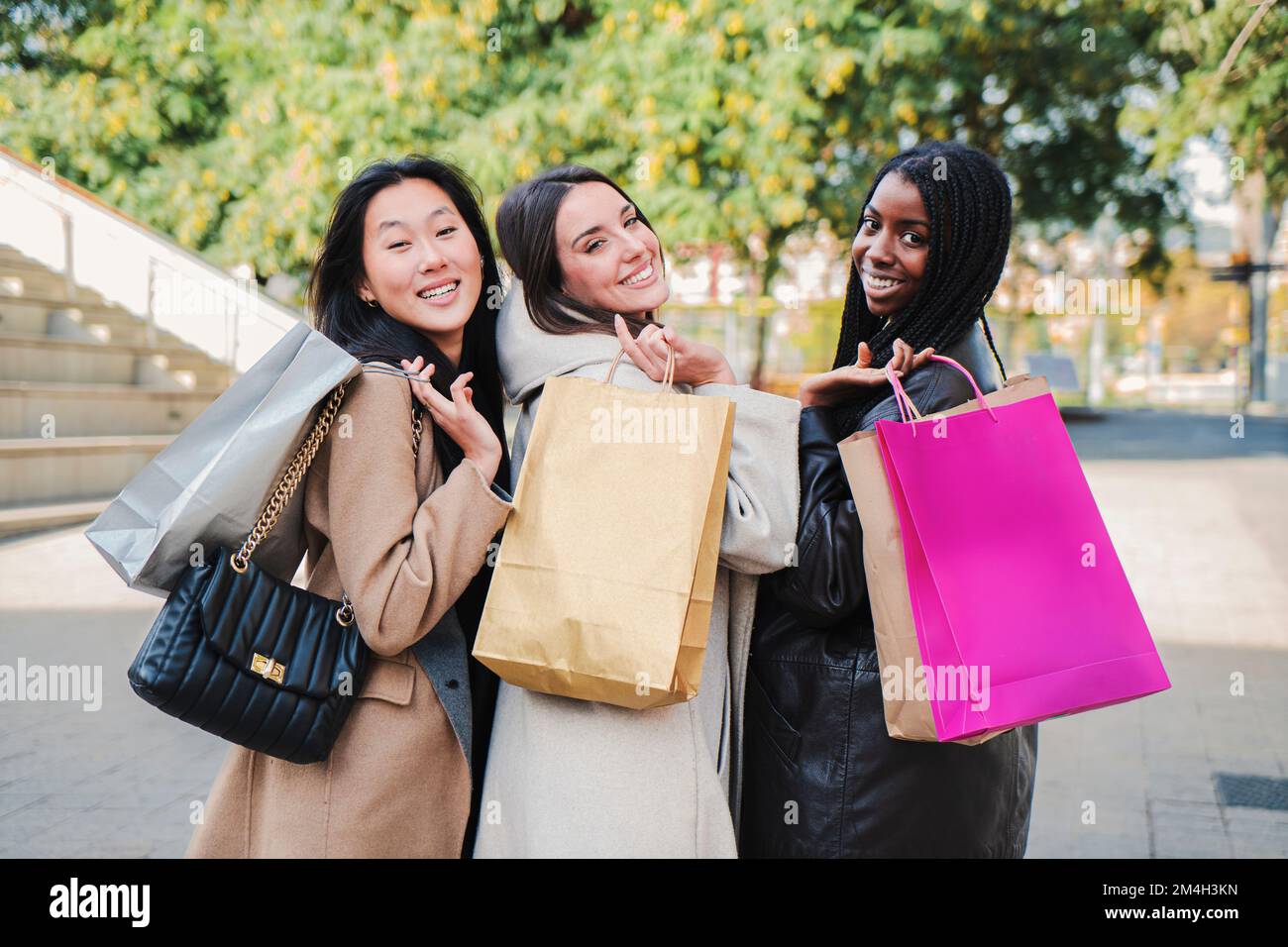 A group of young happy diverse women walking with shopping bags and ...