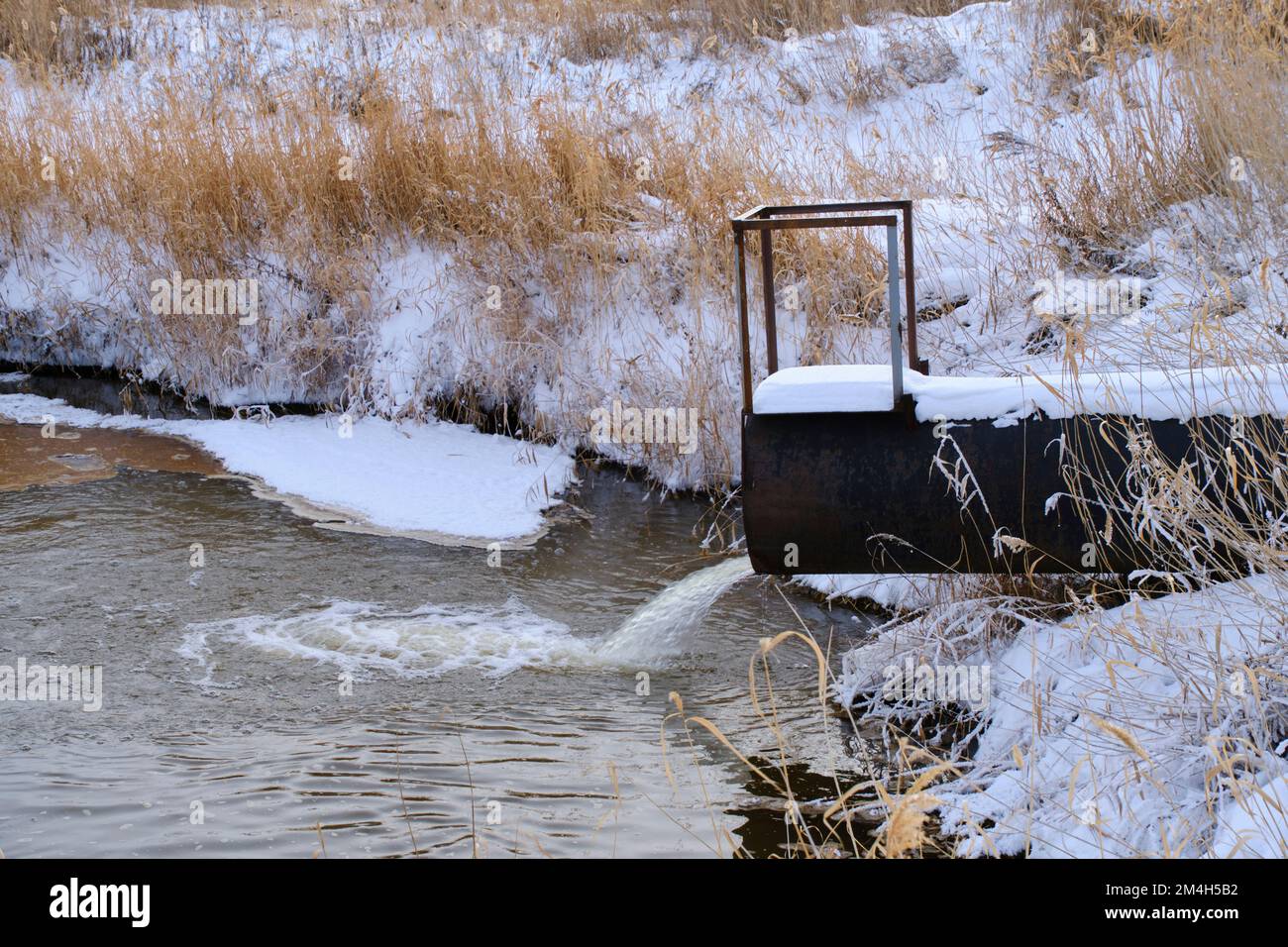 Sewage discharge from pipe into river in winter, river pollution and ...
