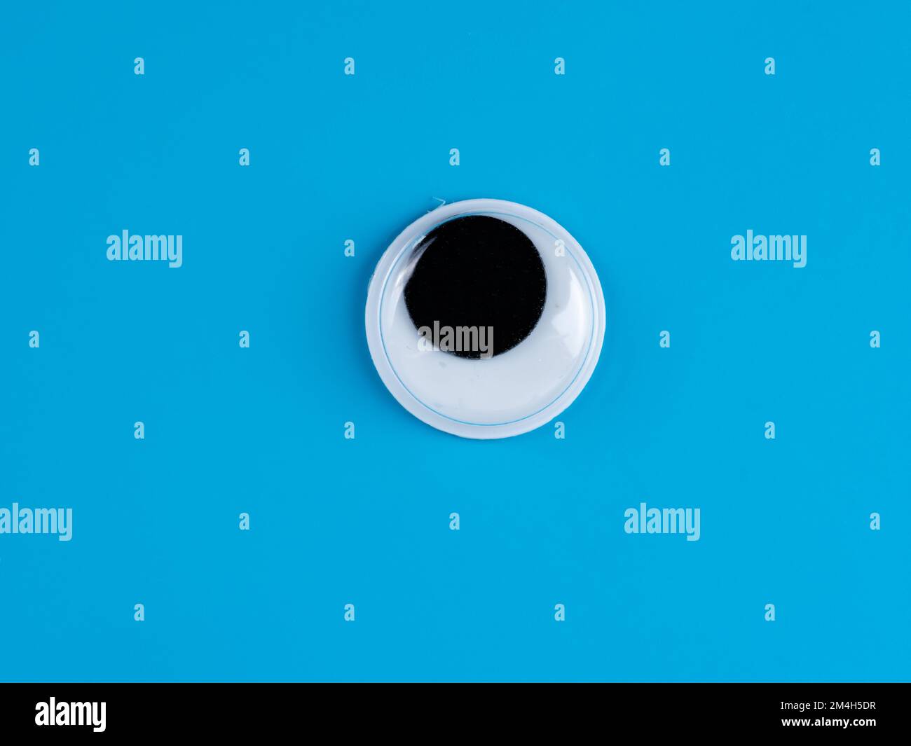 single wobbly googly eye isolated on a light blue background with ...