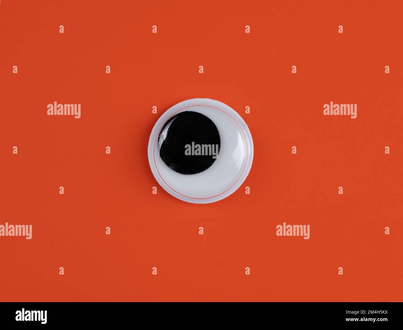single wobbly googly eye isolated on an orange background with ...