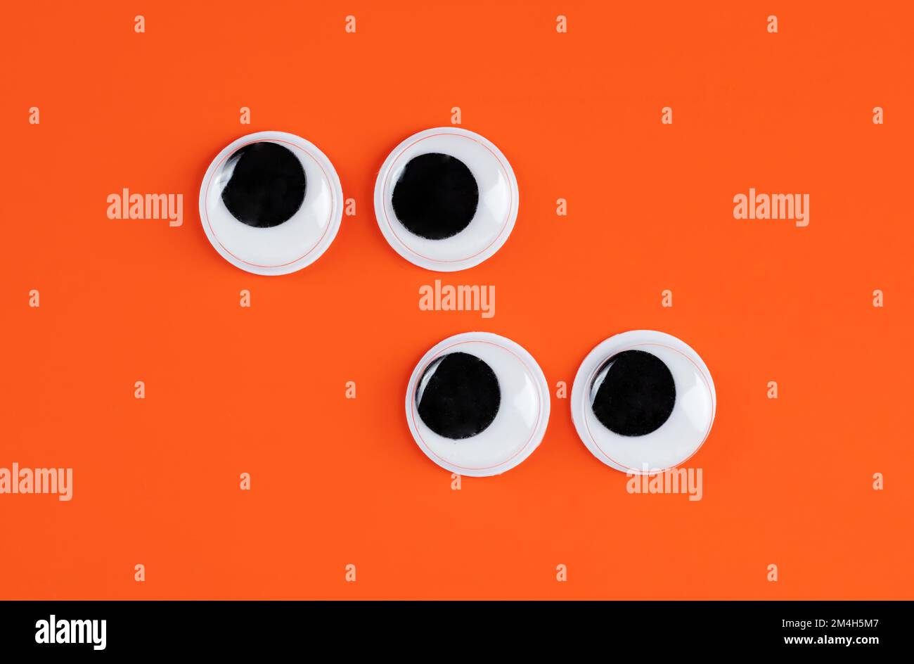 offset pairs of googly eyes funny Isolated on bright orange background ...