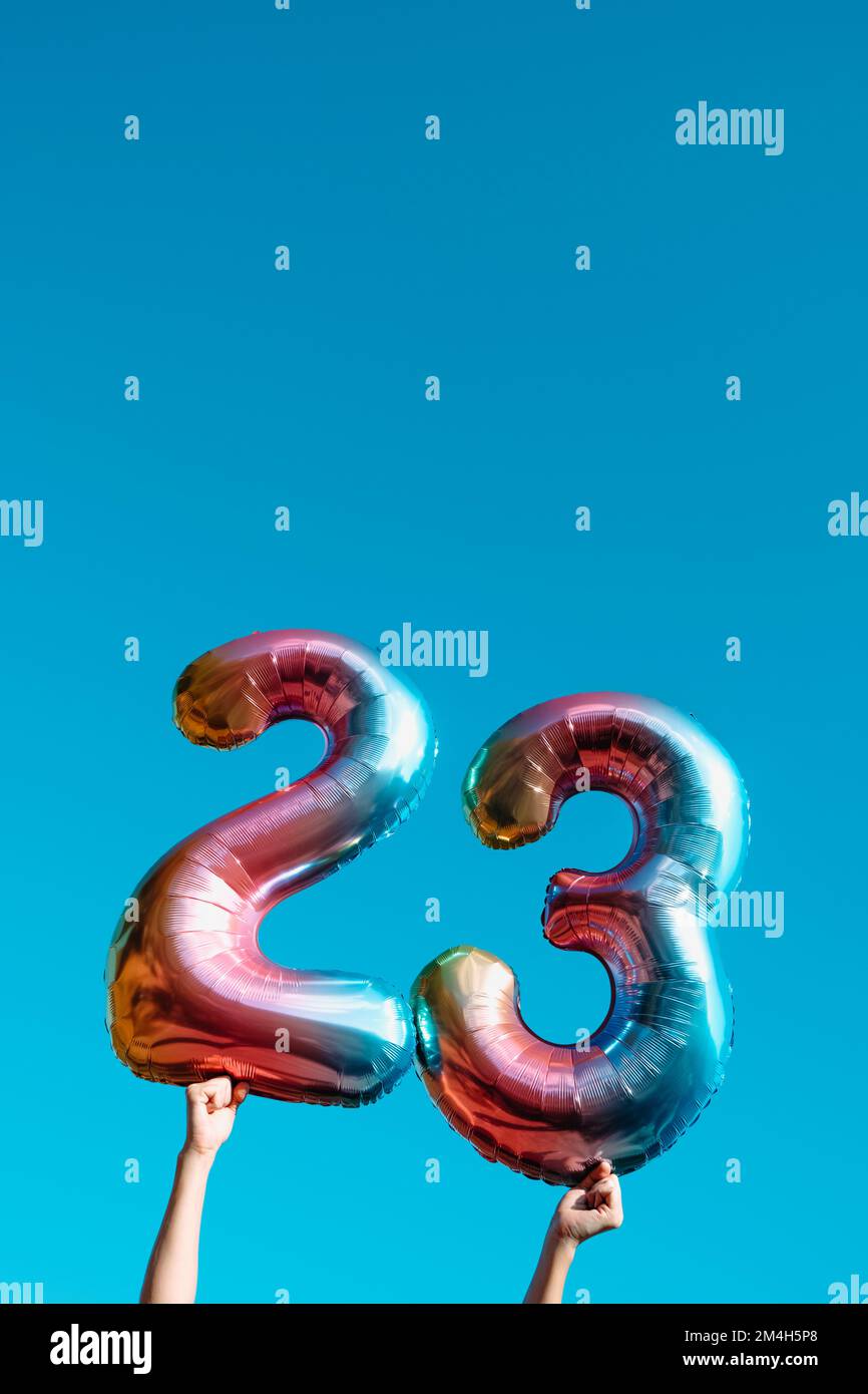 a man holds two number-shaped balloons forming the number 23 on the ...