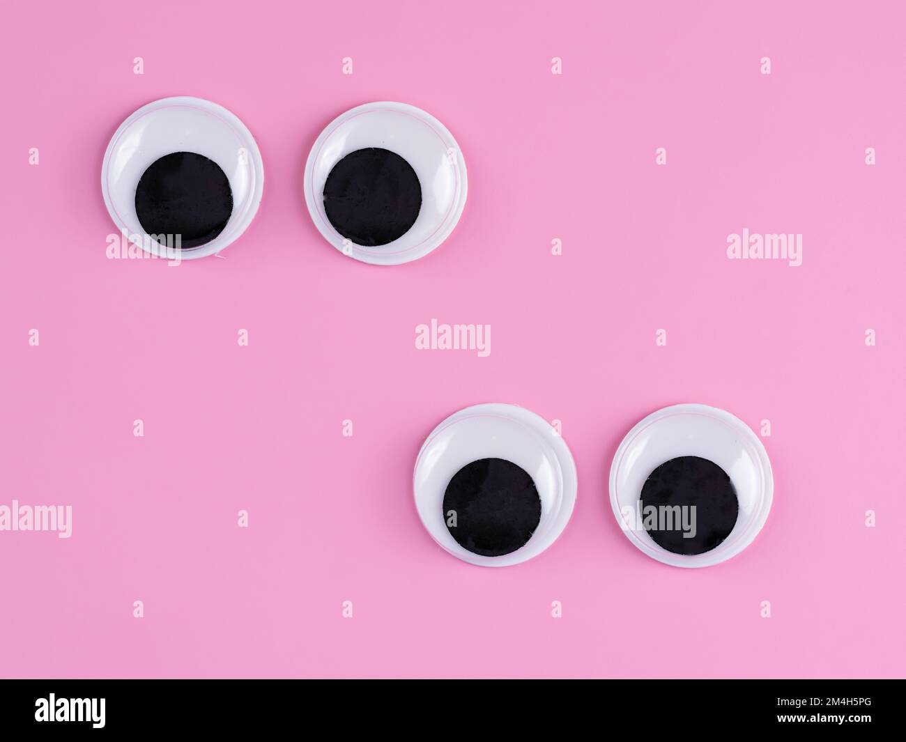 left offset pairs of googly eyes funny Isolated on bright pink ...
