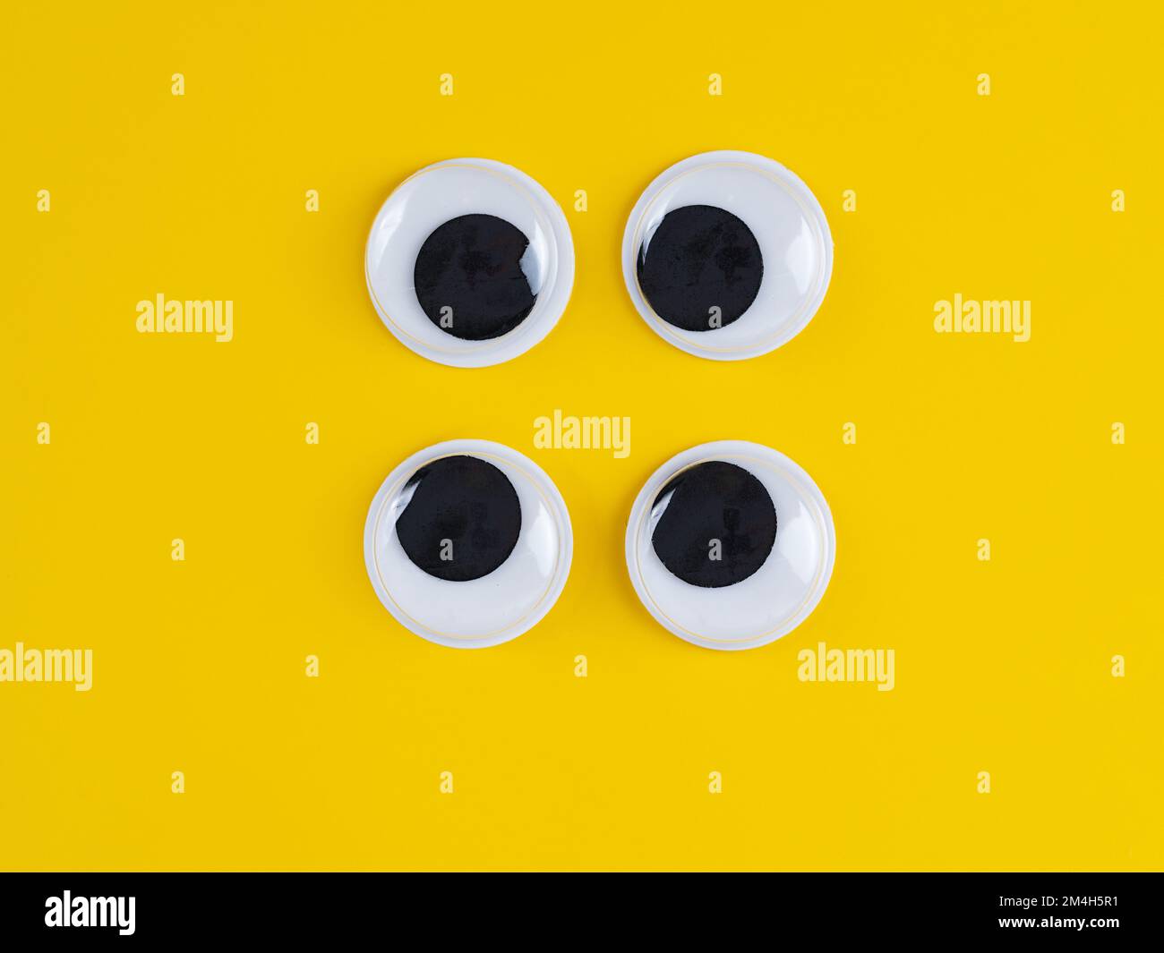 two pairs of googly eyes funny Isolated on bright yellow background ...
