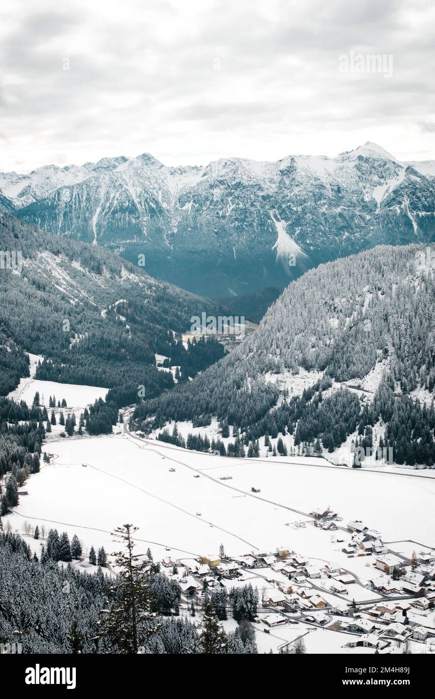 An aerial view of snowy valley surrounded by mountain forests in winter ...