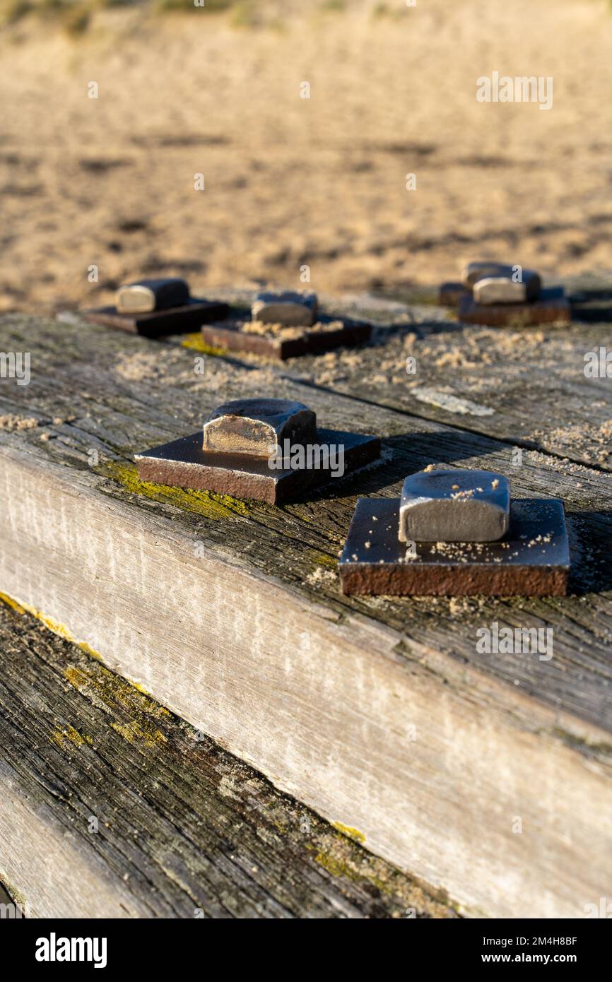 Large Metal Rivett Through Wooden Sleeper On Beach Stock Photo - Alamy